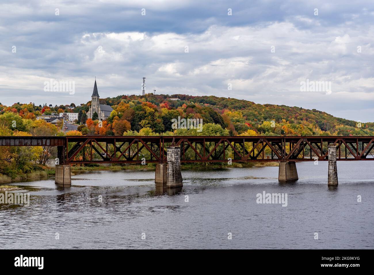 A bridge over the river with buildings and autumn trees on its ...