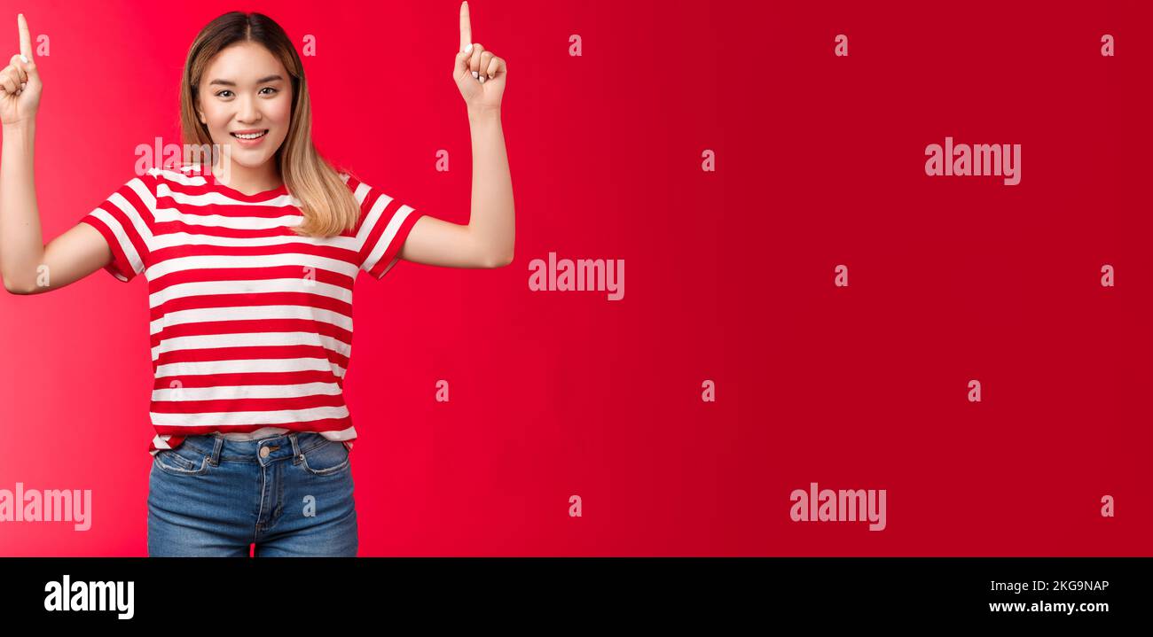 Hey up we go. Cheerful good-looking young asian girl pointing hands up ...