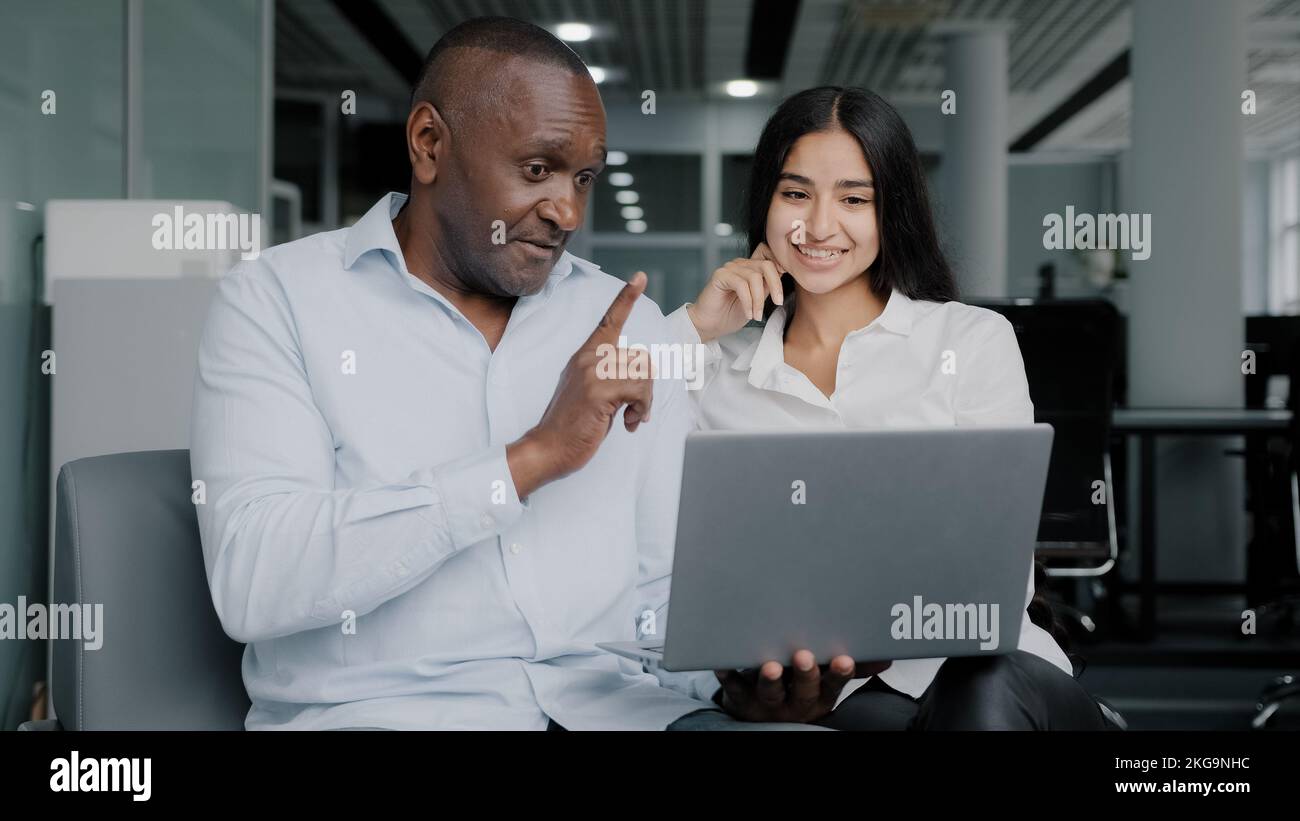 Diverse colleagues two business partners african arabian co-workers discuss internet project on ...