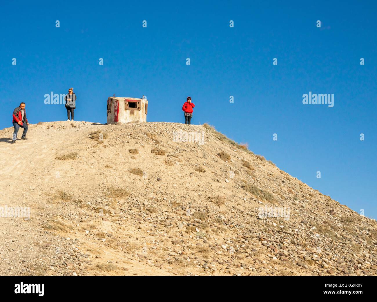 Tourists on the slope beside concrete bunker. Black canyon, Kazakhstan ...