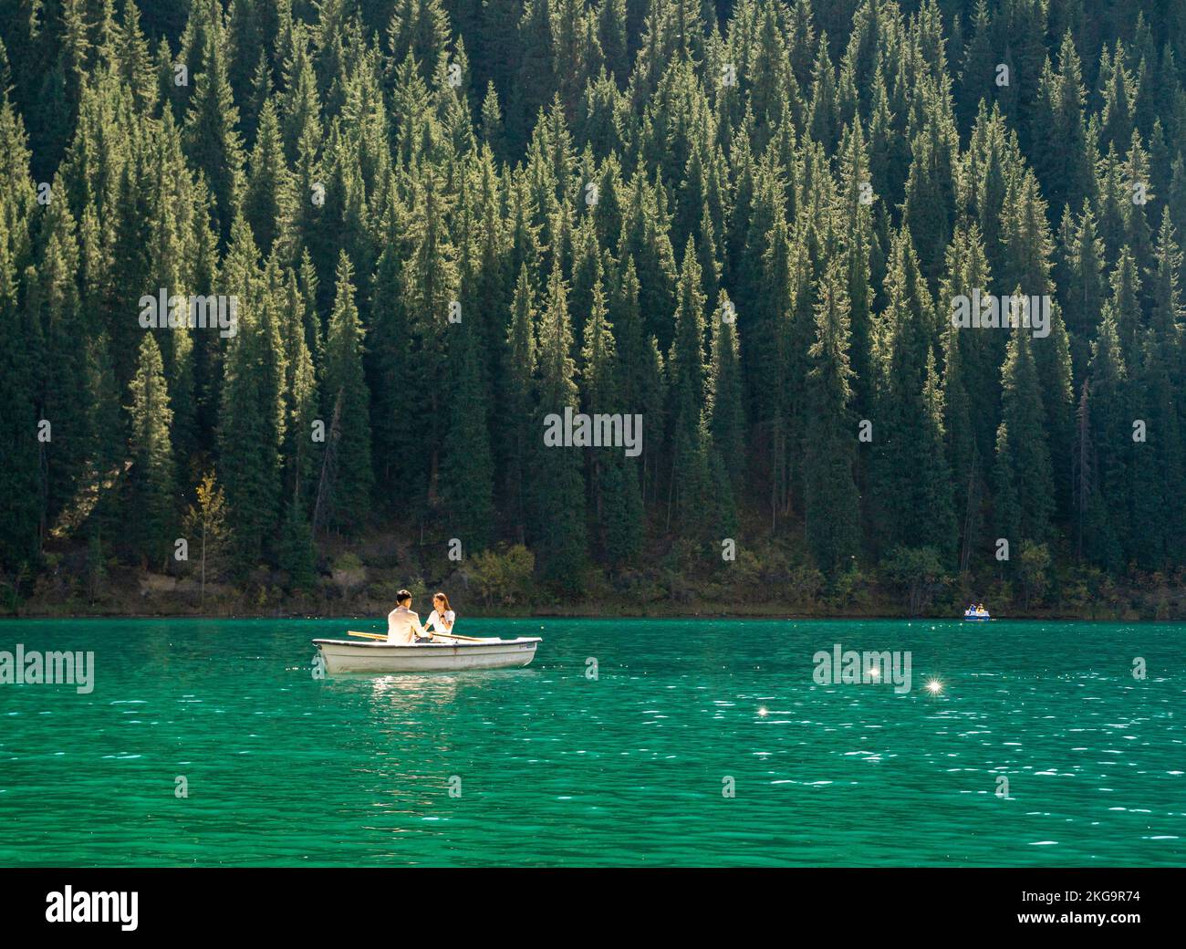 Green lake water opposite spruce trees covering the hill. The boat ...