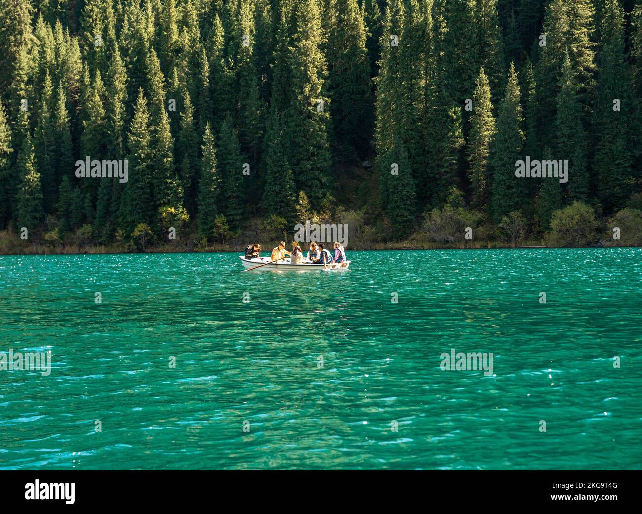 Green lake water opposite spruce trees covering the hill. The boat ...