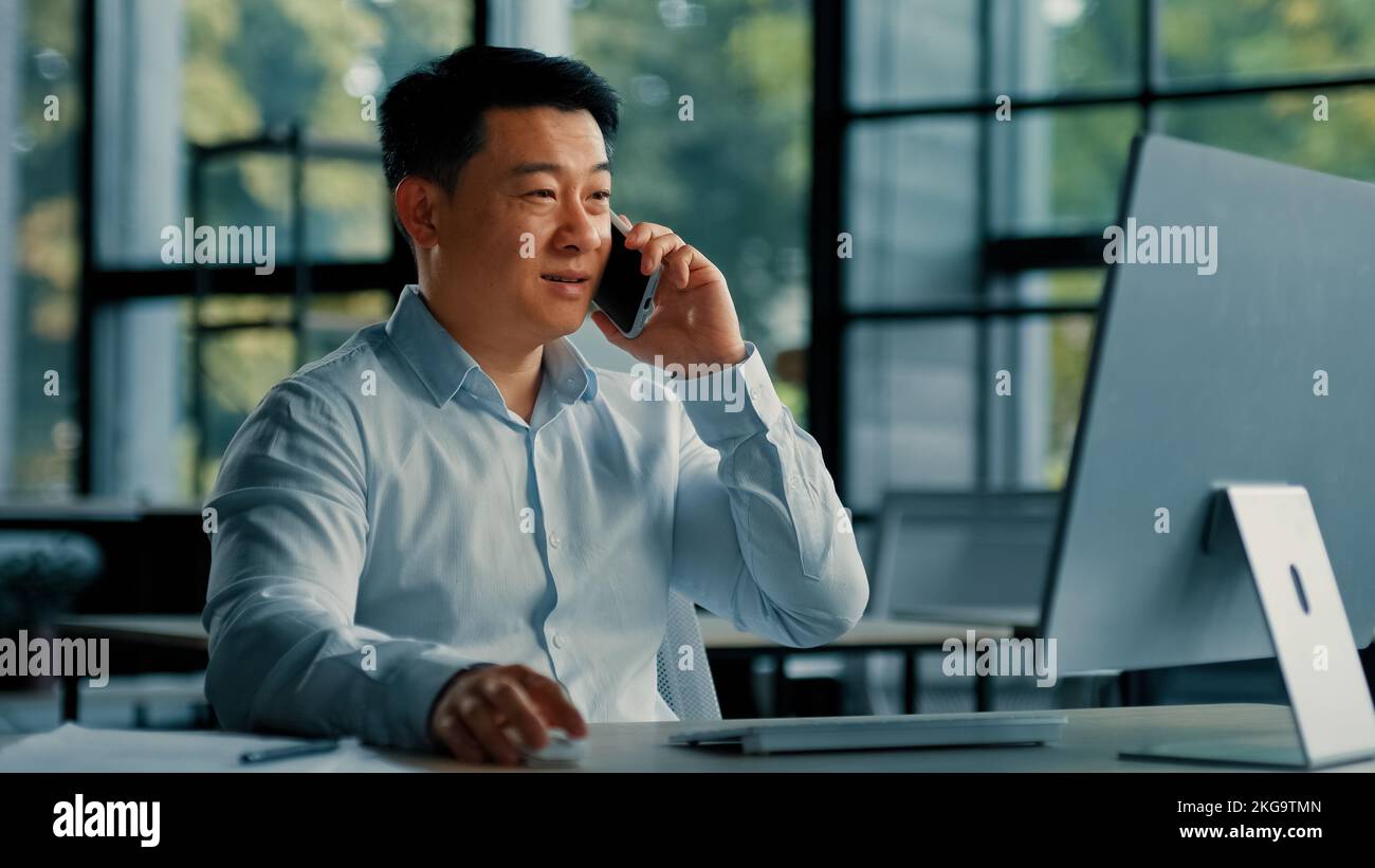 Confident adult 40s businessman asian japanese man consultant sit in office workplace speak ...