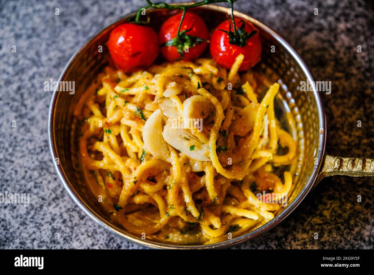 A close up of pasta bucatini with cheese and garlic with full tomatos ...