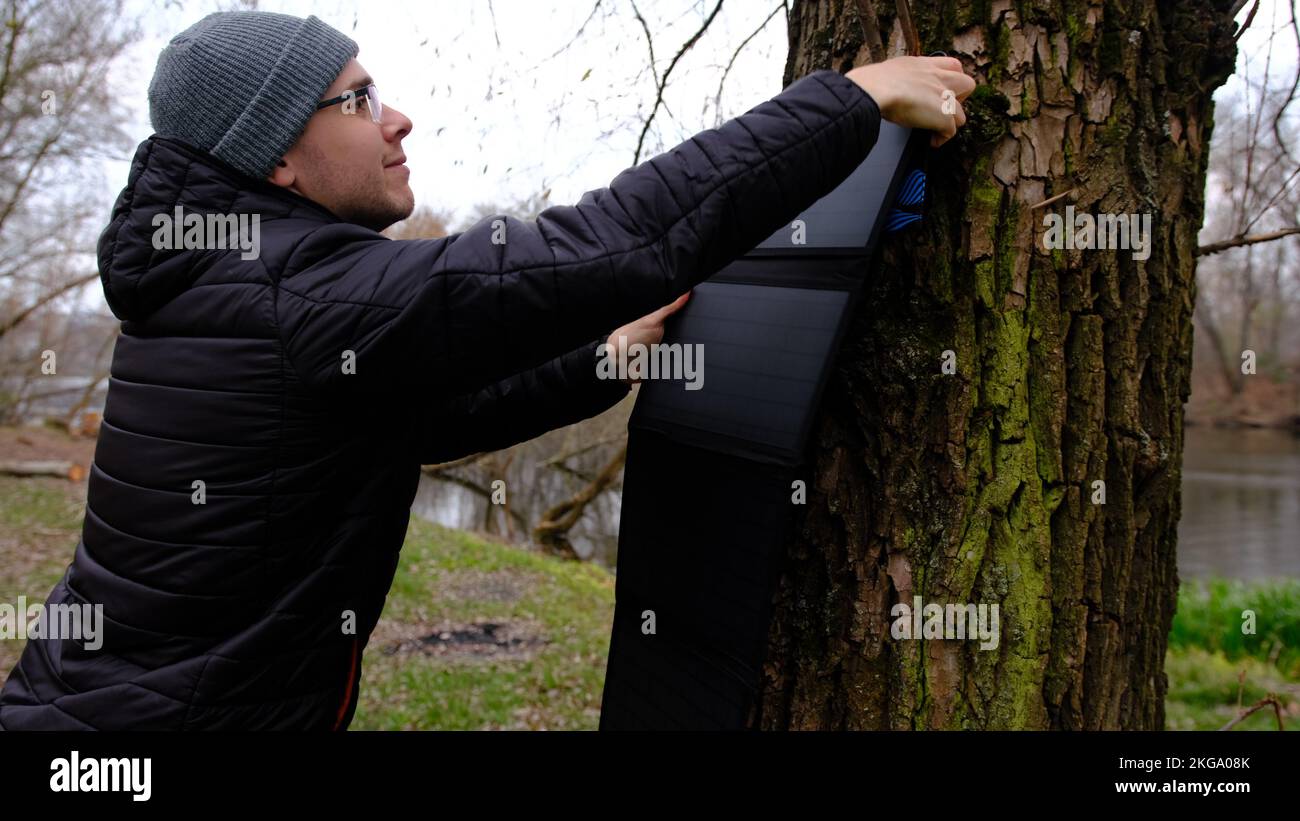 Man hang solar panel on tree for charging smartphone by mutlipurpose ...