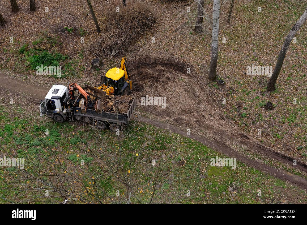 Landscaping company using tractor and truck with crane to clear land of ...