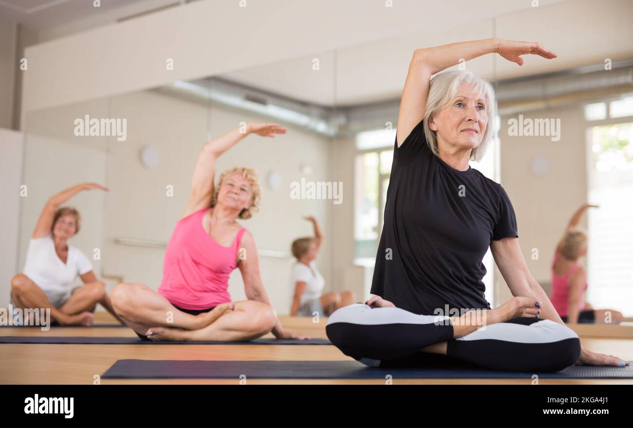 Active mature woman performing stretching during group training Stock ...