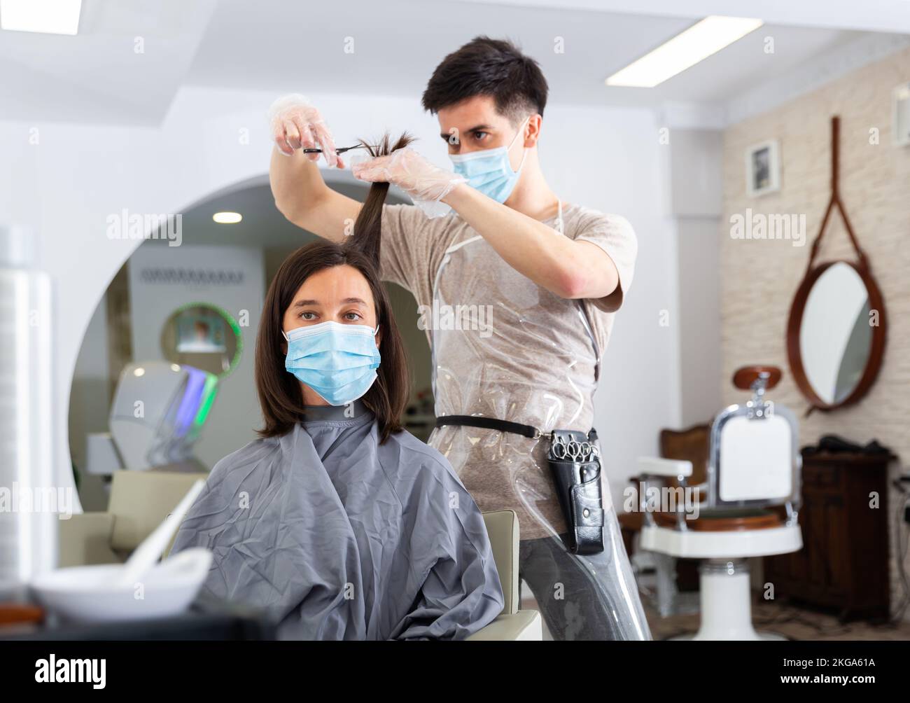 Man doing haircut for woman in salon using face masks Stock Photo - Alamy