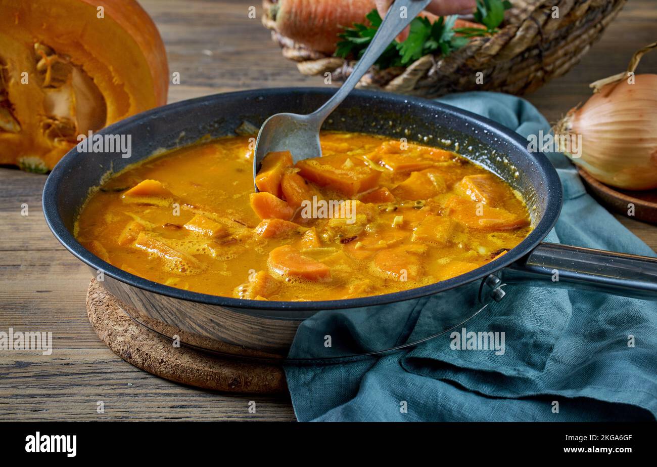 pumpkin and carrot stew in a cooking pan on rustic kitchen table ...