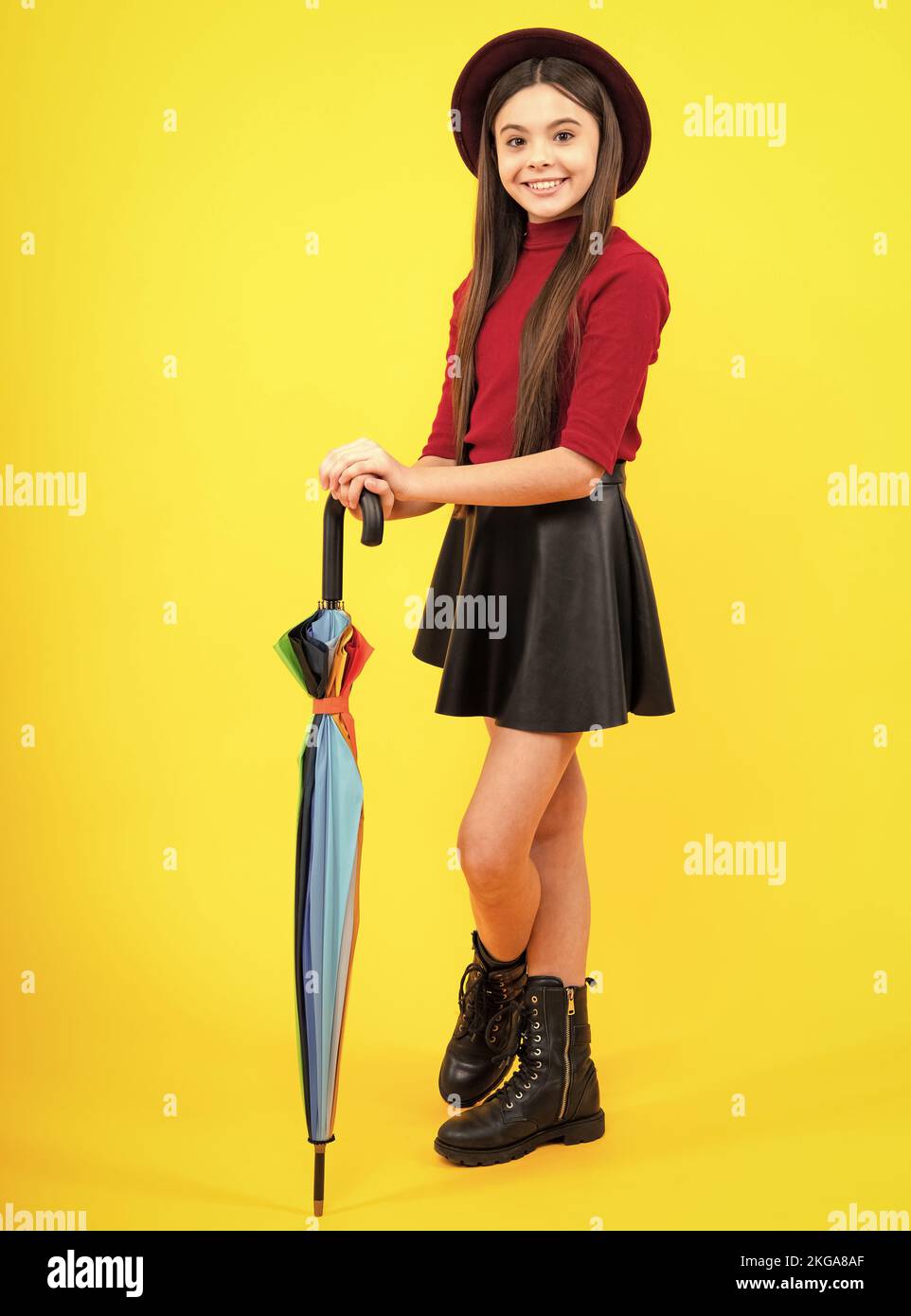 Teen girl with umbrella in autumn weather isolated on yellow background ...