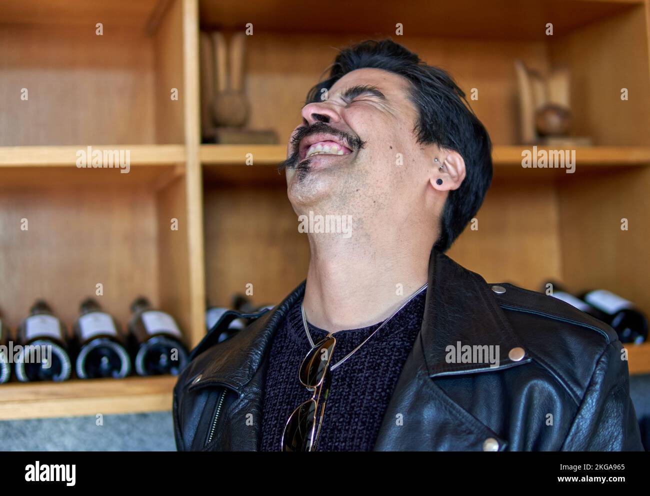 latin man at a wine tasting laughing with his head back very happy ...