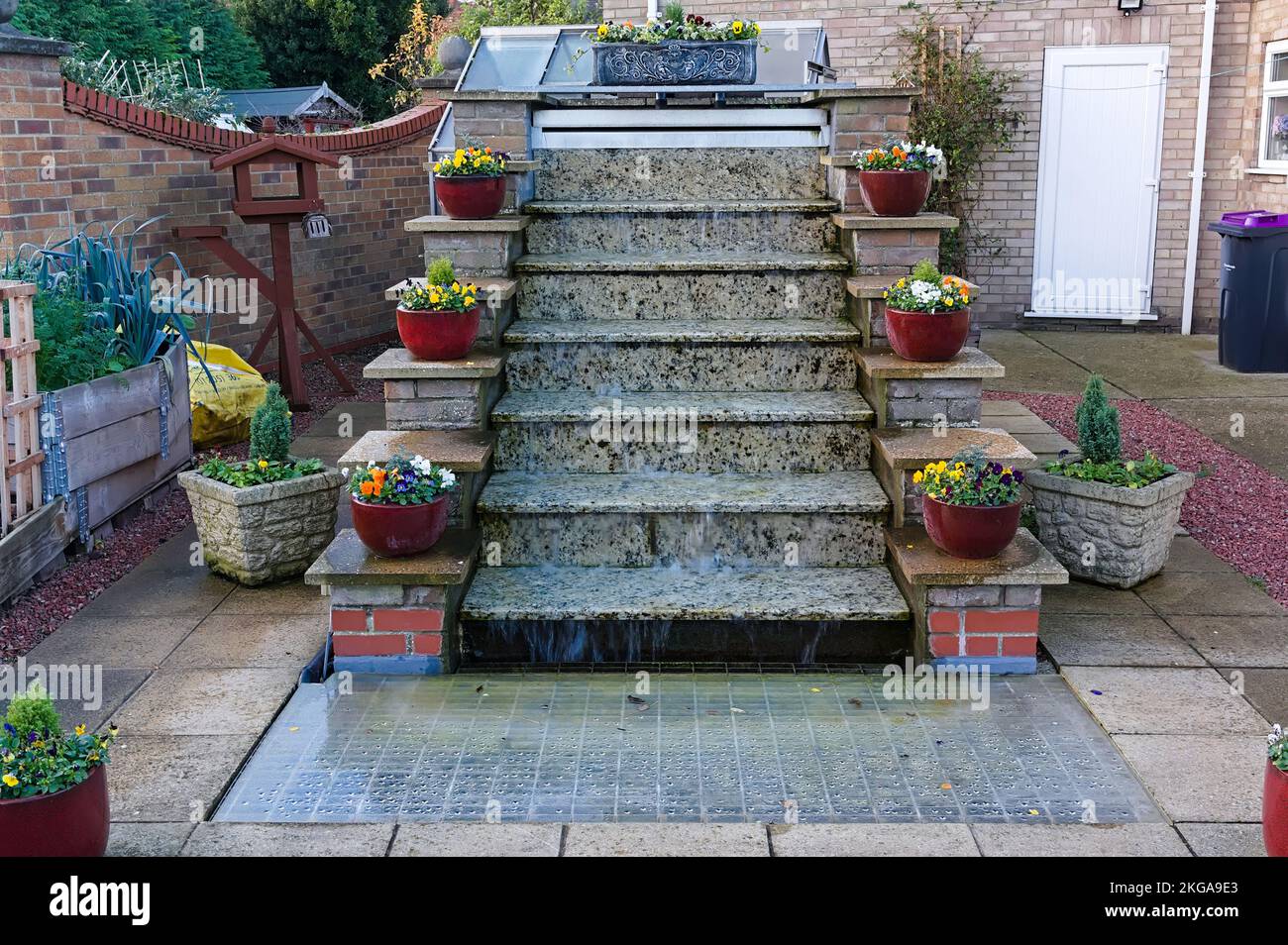 beautiful steps waterfall in a garden with symmetrical potted plants on ...