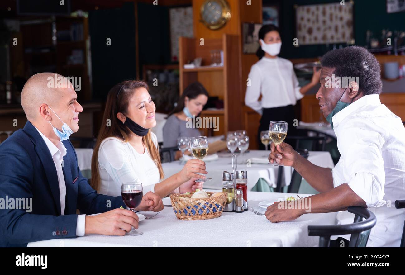Cheerful people in masks having dinner in restaurant Stock Photo - Alamy