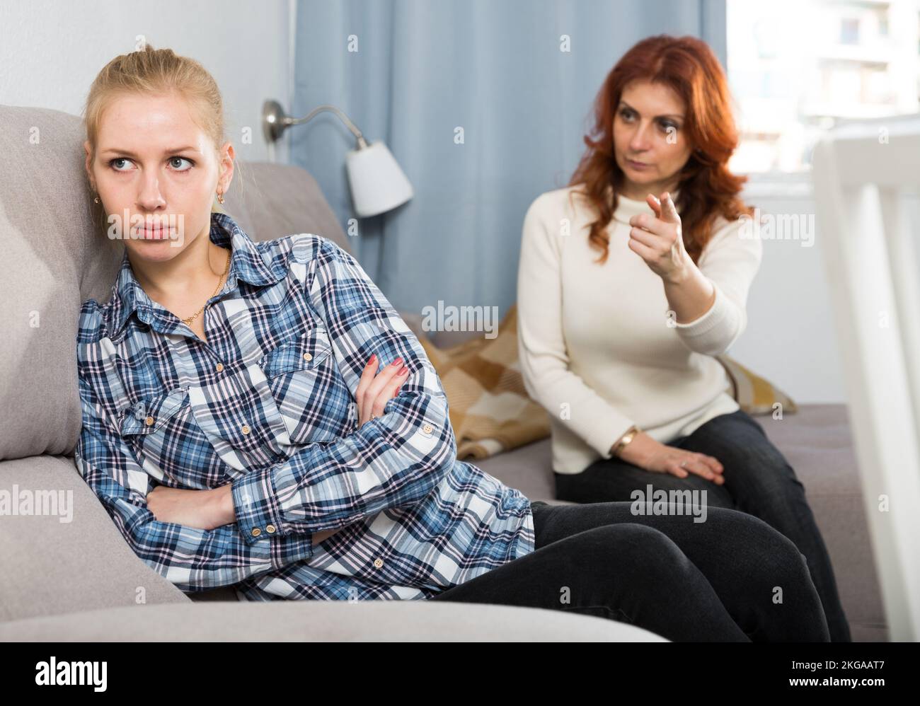 Sad mature female and daughter sitting at sofa and having quarrel Stock ...