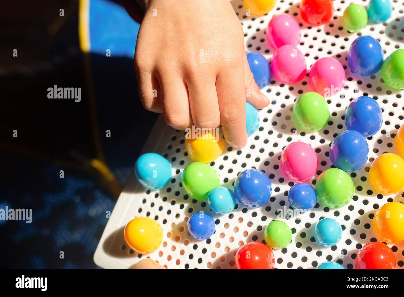 Baby plays with colourful mosaics on white surface. Kids hand with ...
