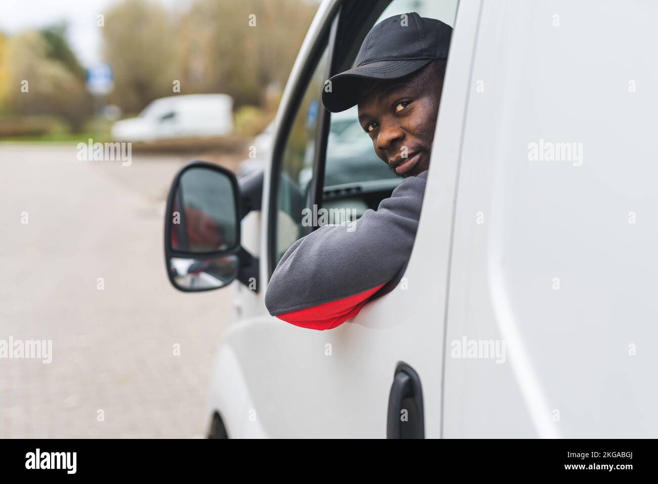 Back outdoor closeup view of Black male courier in black baseball hat ...