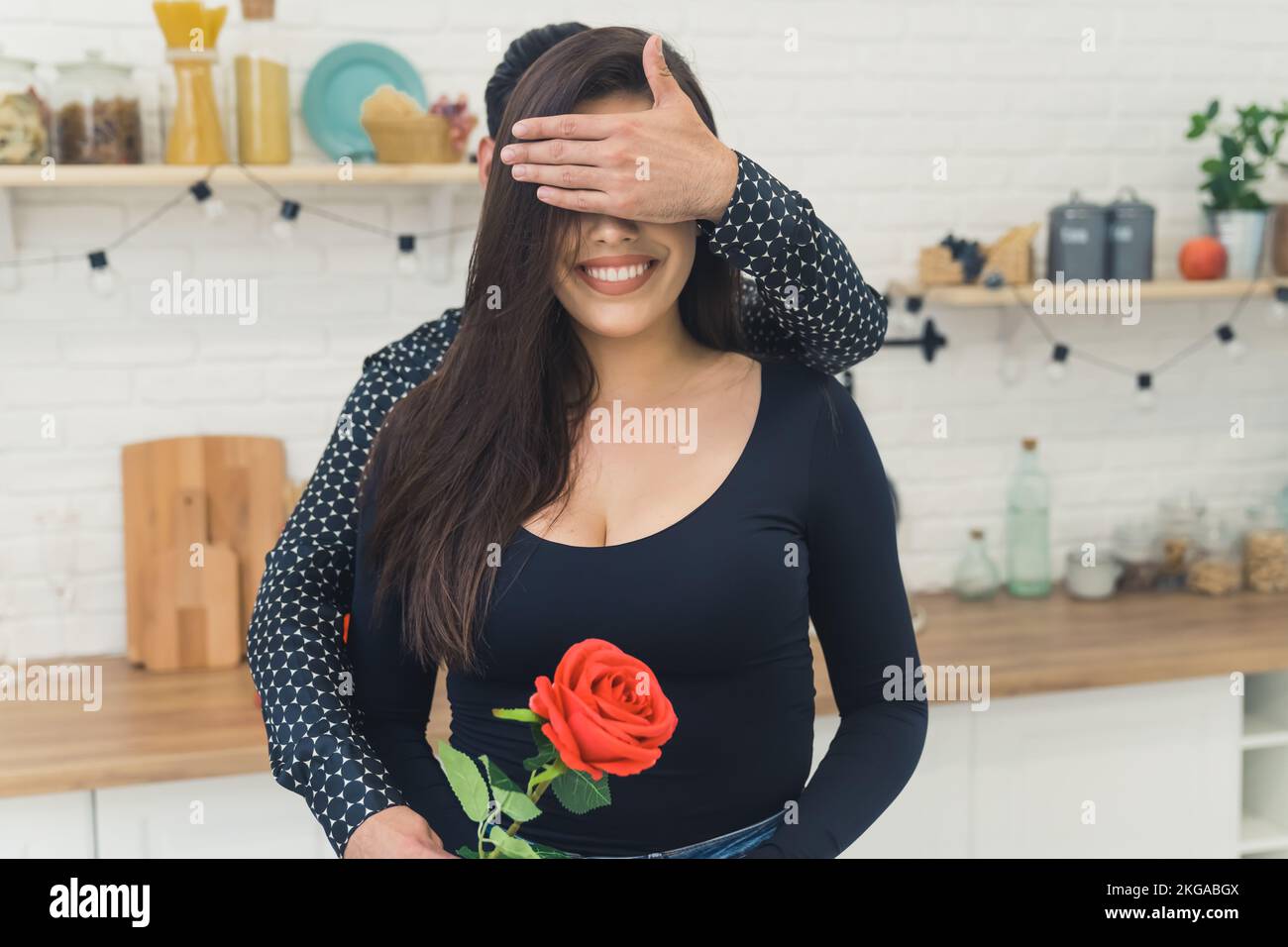 A young man standing behind his beautiful girlfriend with long dark ...