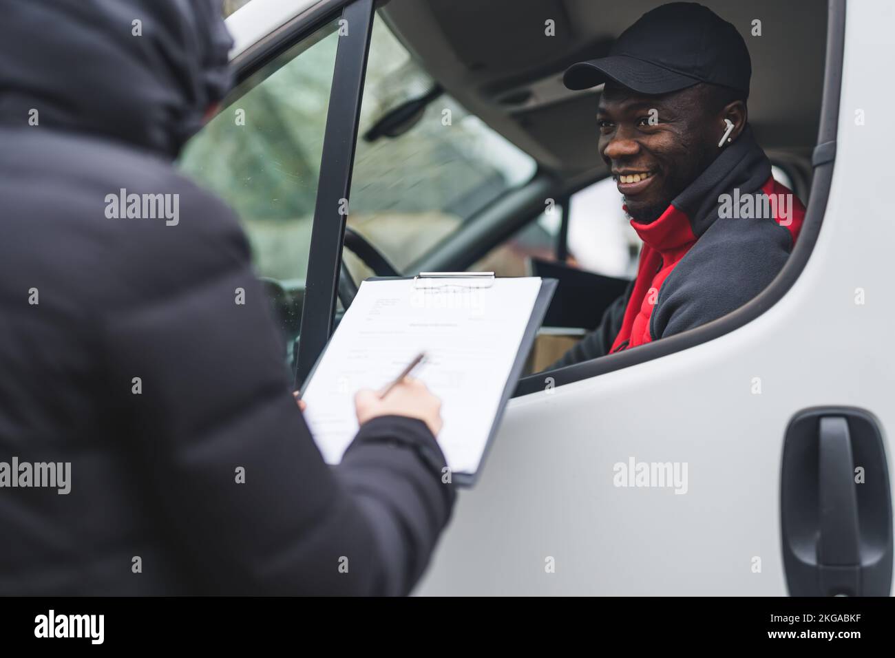 African-American delivery truck male driver smiling at unrecognizable ...