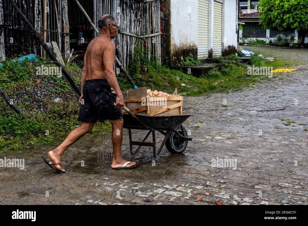 Worker man carrying goods in a wheelbarrow to the store through the ...