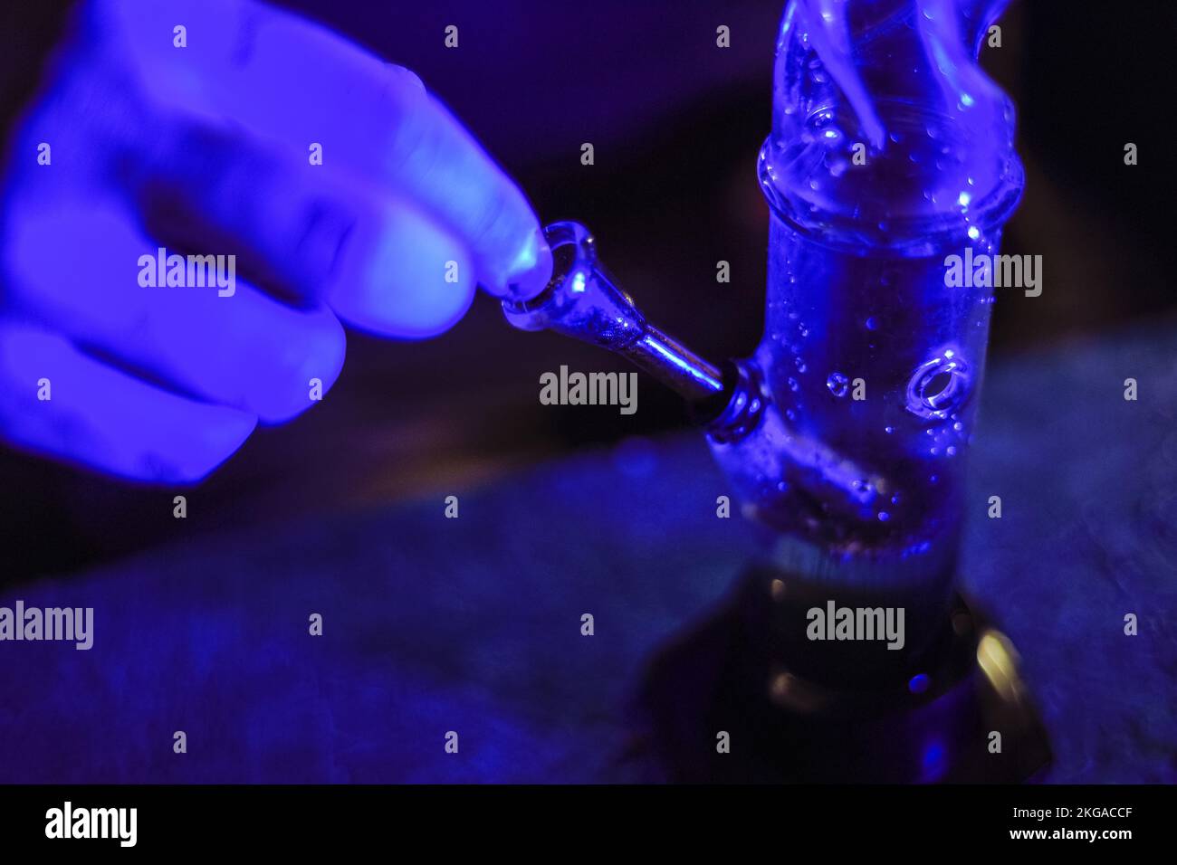 Male hands clog a bong with marijuana. Drugs and drug addict. The man ...