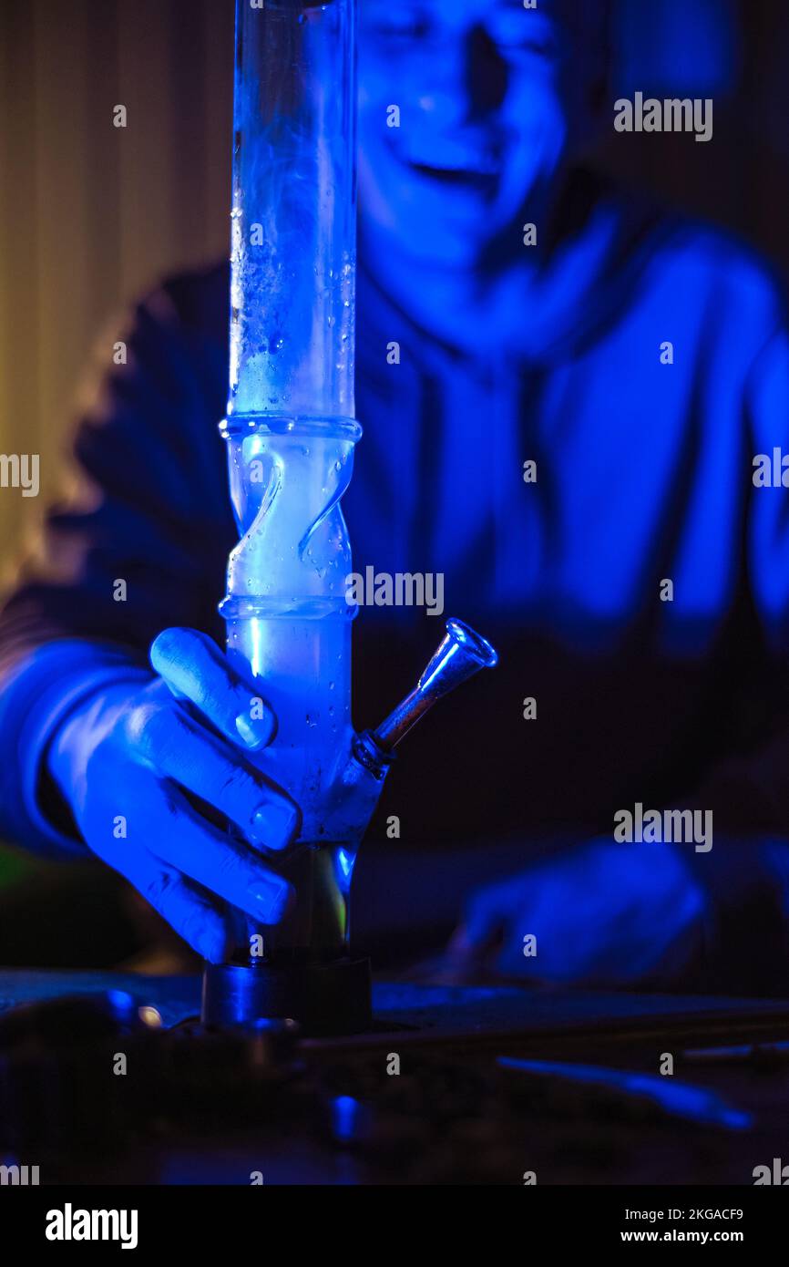 Male hands clog a bong with marijuana. Drugs and drug addict. The man ...