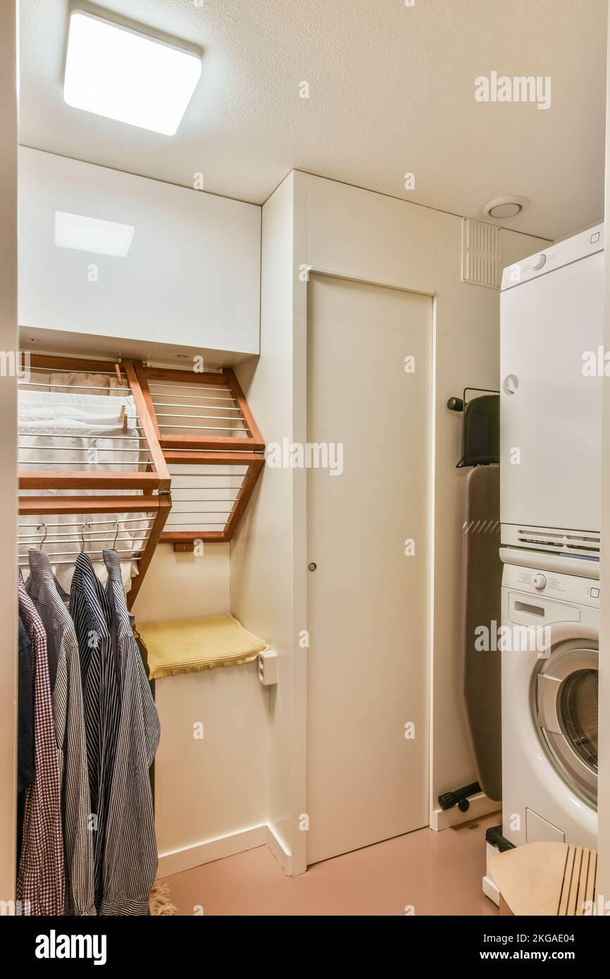 Interior of cozy bright laundry room with white walls and ironing board ...