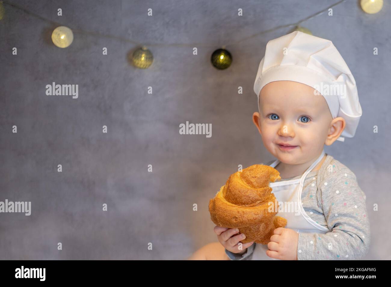 a cute little girl in a chefs hat and an apron sits at home on the ...