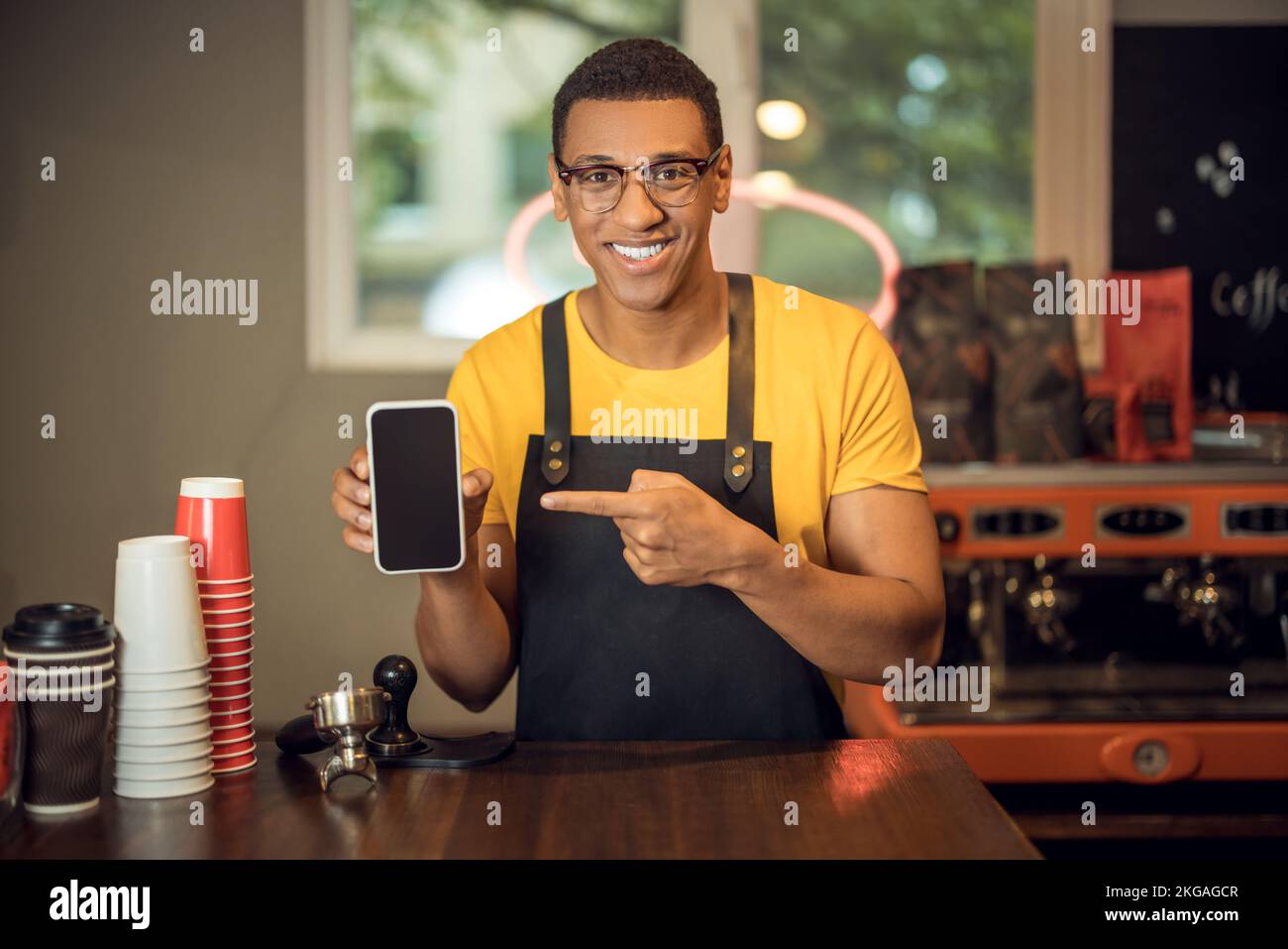 Joyous cafe worker showing off his cellphone in the workplace Stock ...