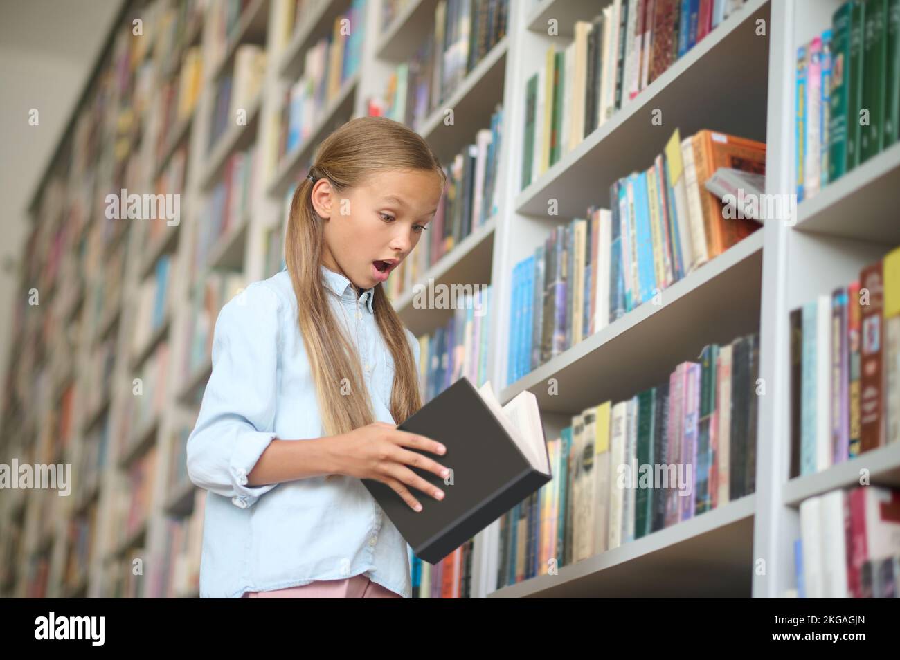 Cute girl searching for a book in the school library Stock Photo - Alamy