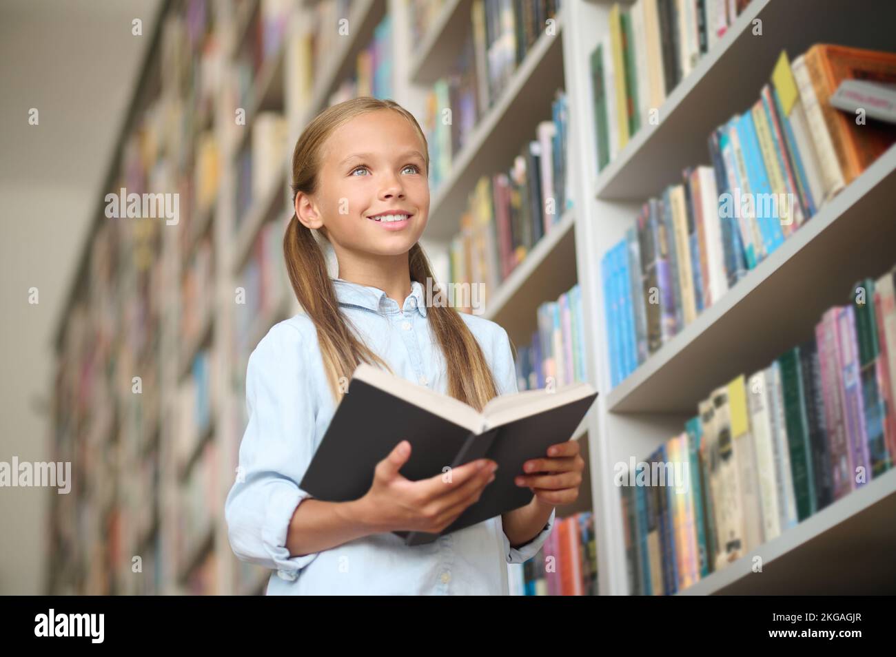 Cute girl searching for a book in the school library Stock Photo - Alamy