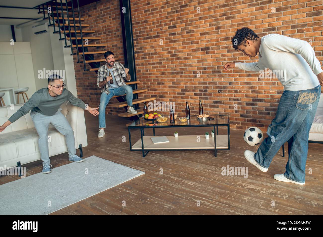 Cheerful young man watching his friends playing a sports game Stock ...