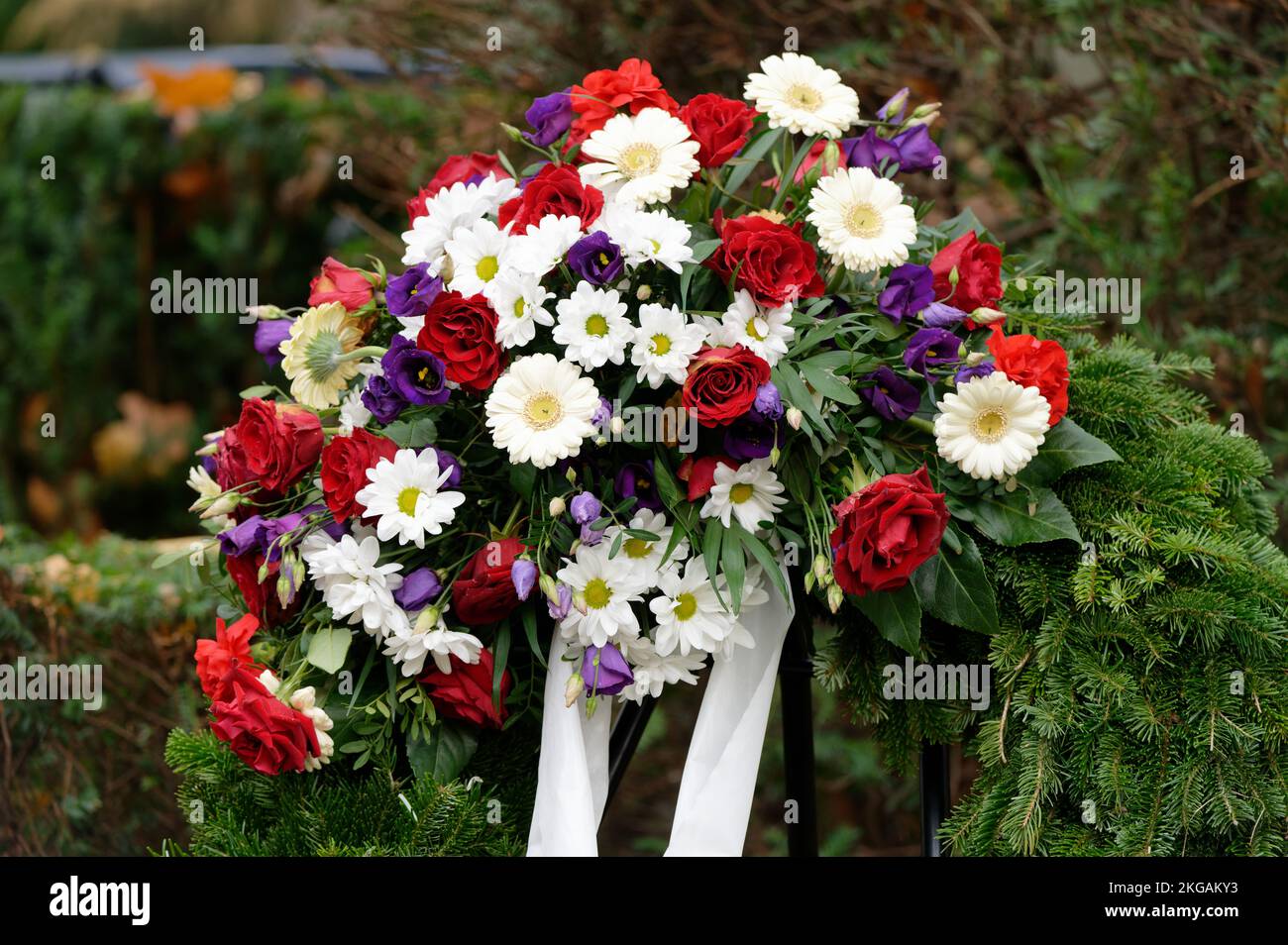 funeral wreath in a cemetery with colorful flowers and bow on a metal ...