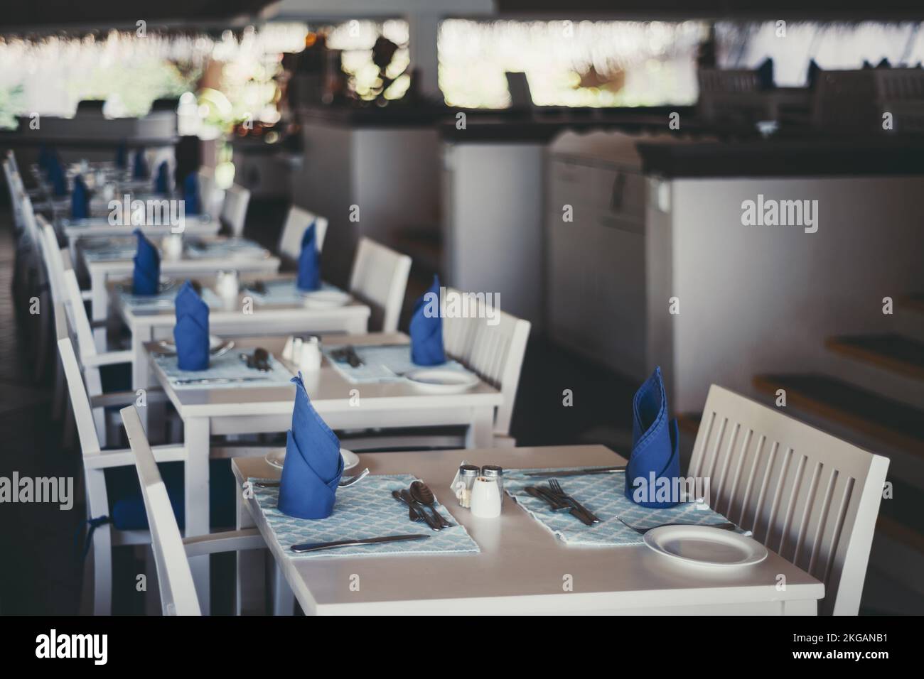An indoor resort canteen with many made tables prepared for lunch ...