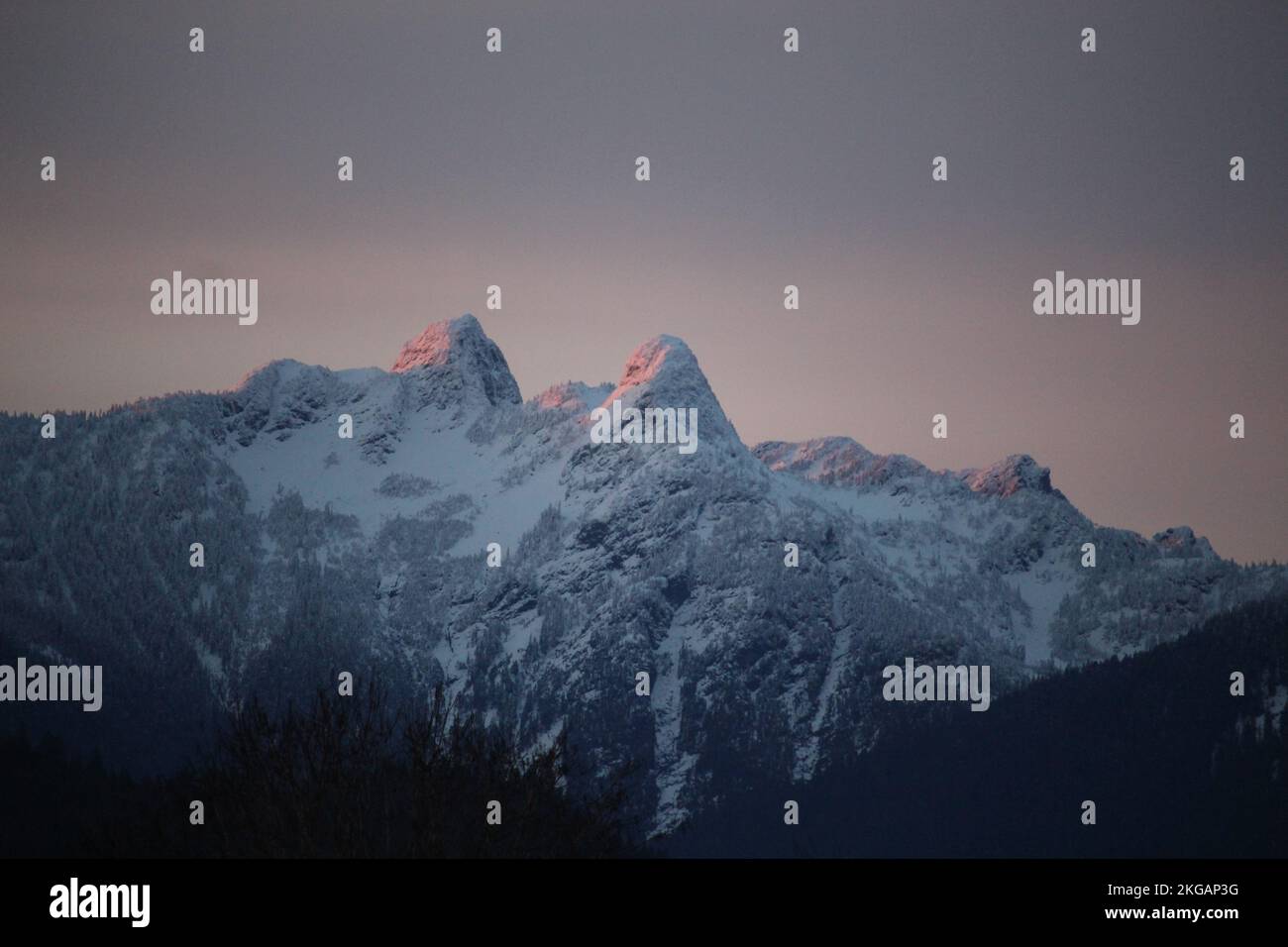 A scenic view of snow-capped mountain in the countryside during sunset ...