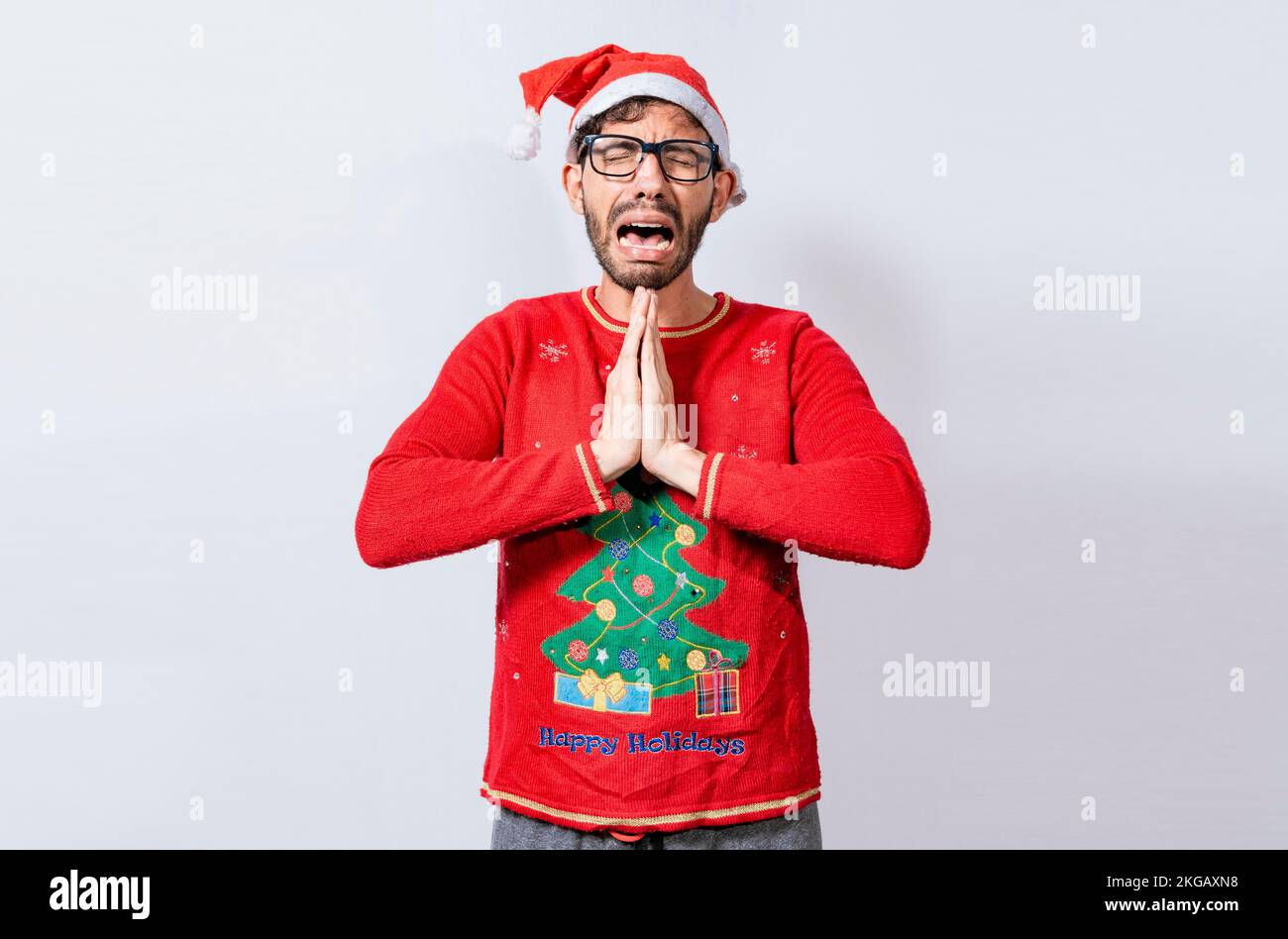 Man with christmas hat with hands together in pleading gesture ...