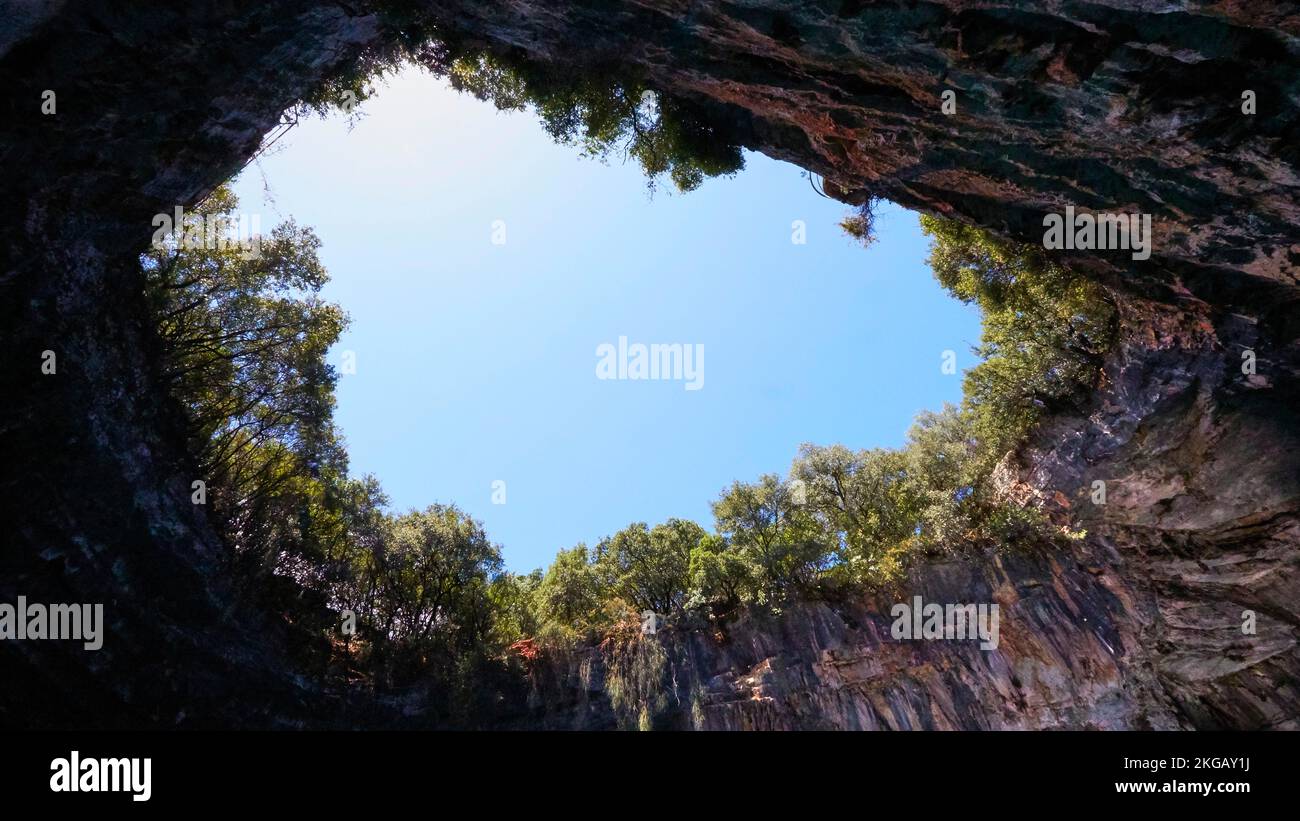 Opening in cave ceiling, blue sky, trees, Melissani cave, underground ...
