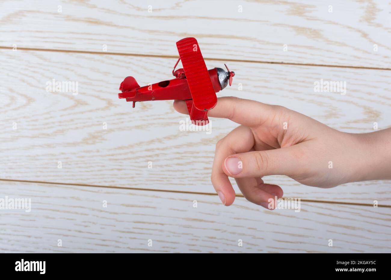 Hand holding a red toy plane on a on wooden texture Stock Photo - Alamy