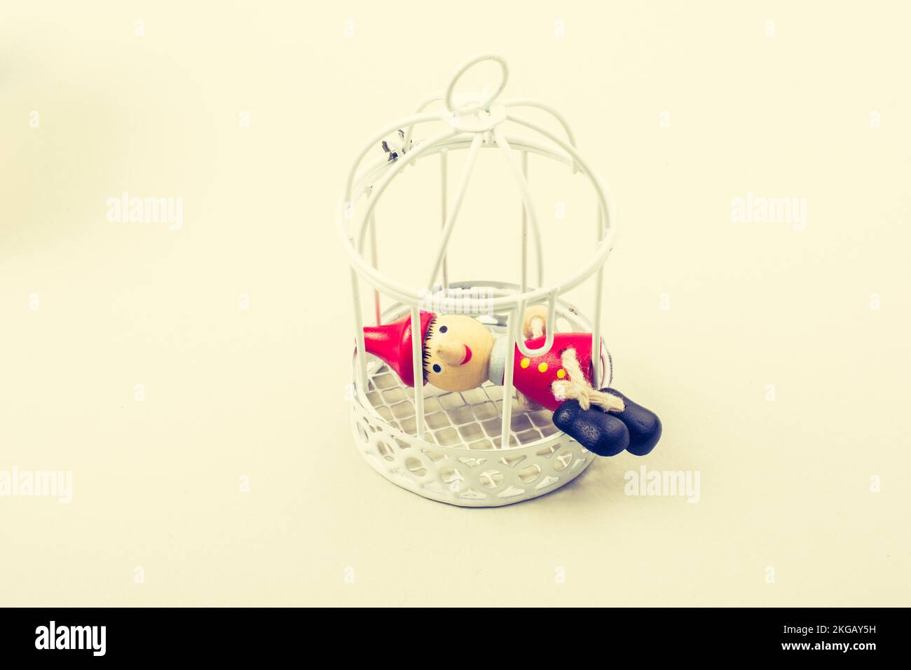Metal cage and Little puppet pinocchio made of wood Stock Photo - Alamy