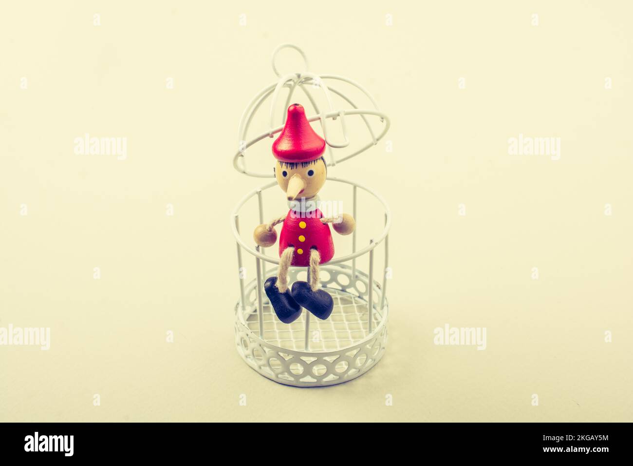 Metal cage and Little puppet pinocchio made of wood Stock Photo - Alamy