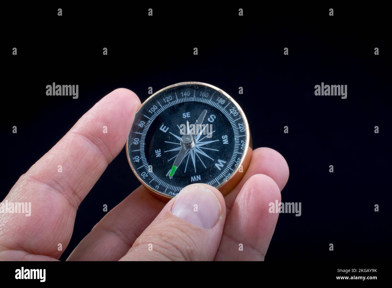 Child hand holding a compass on a black background Stock Photo - Alamy