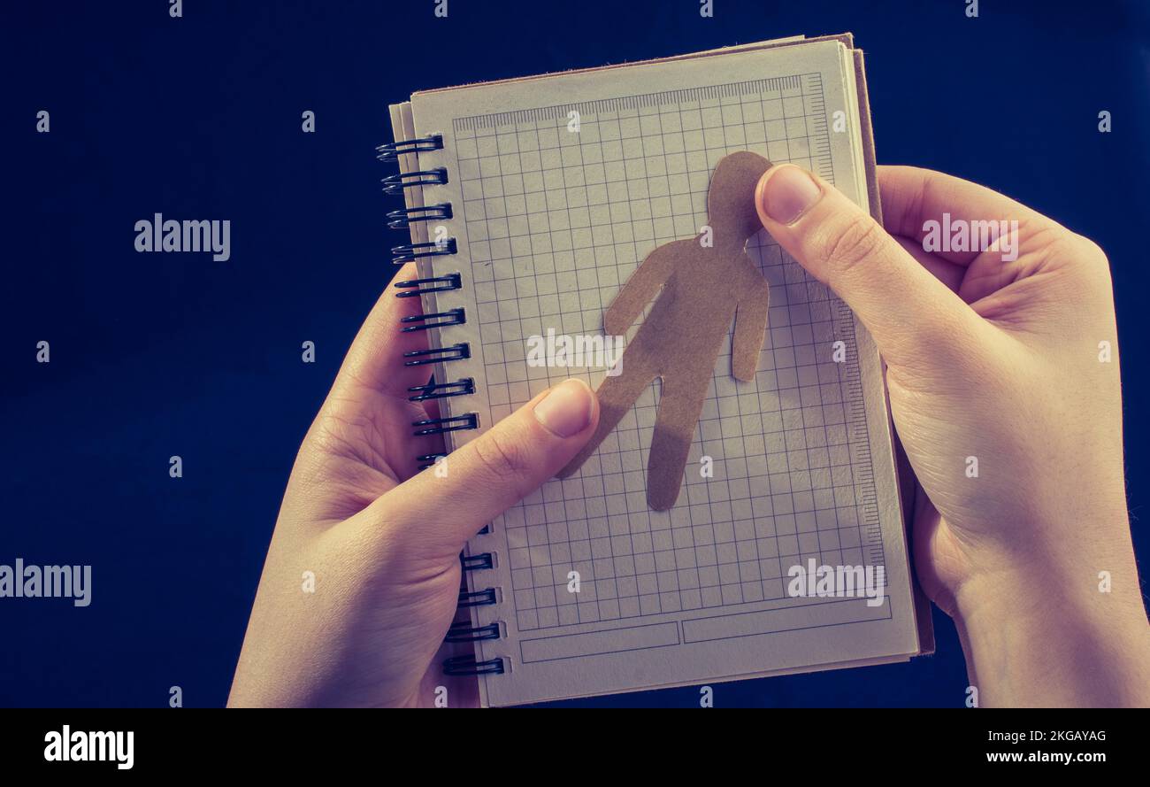 Man shape cut out of paper in notebbok in hand Stock Photo - Alamy