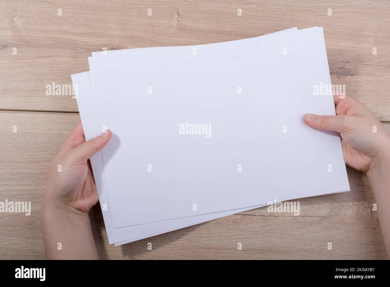 Hand holding sheets of paper on a wooden background Stock Photo - Alamy