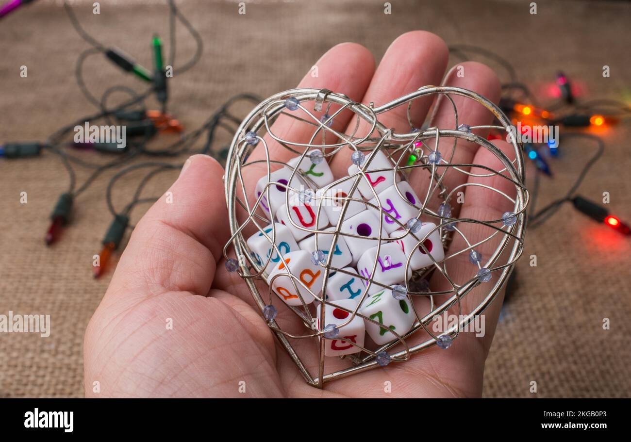 Hand holding a heart cage full of alphabet dice on a Christmas light ...