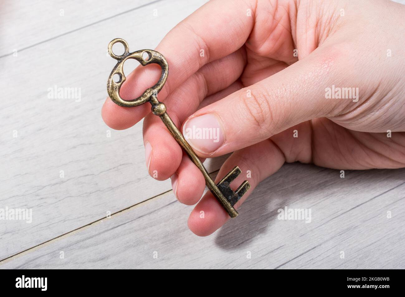 Hand holding a retro styled decorative key on wooden texture Stock ...