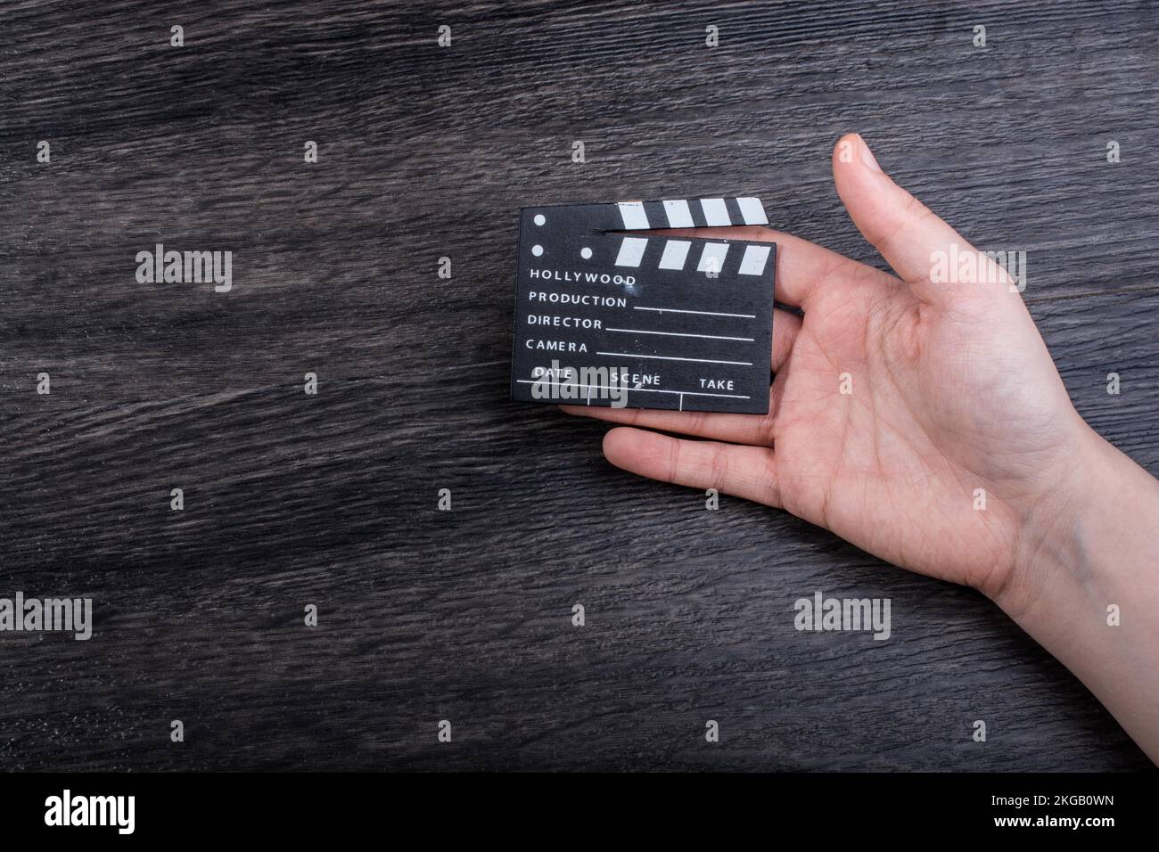 Hand holding movie clapper on a dark background Stock Photo - Alamy