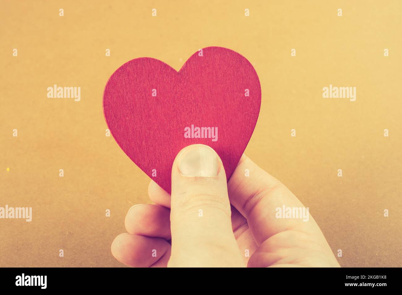 Red color heart shaped object in hand on dotted paper Stock Photo - Alamy