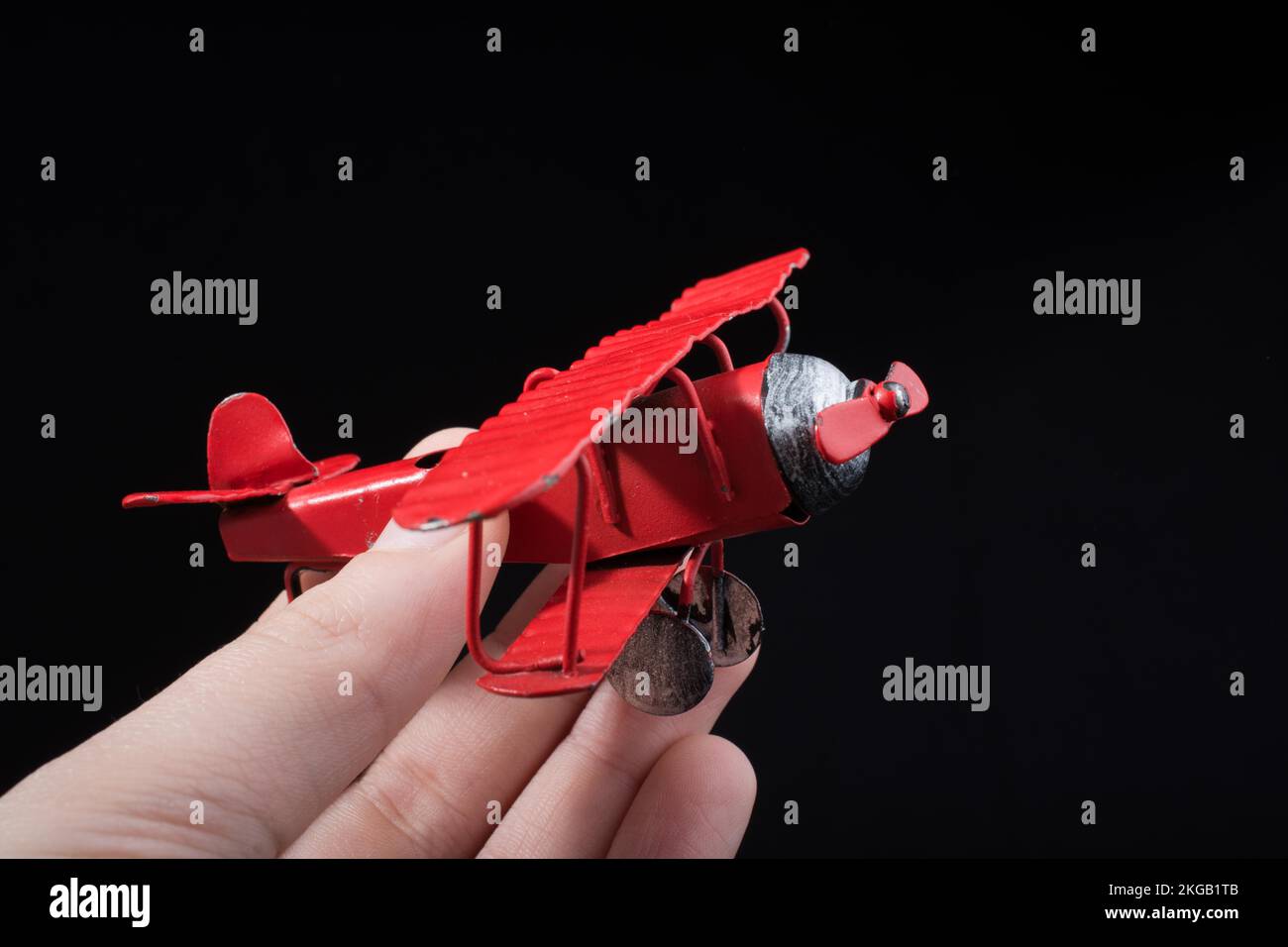 Hand holding a red toy plane on a black background Stock Photo - Alamy