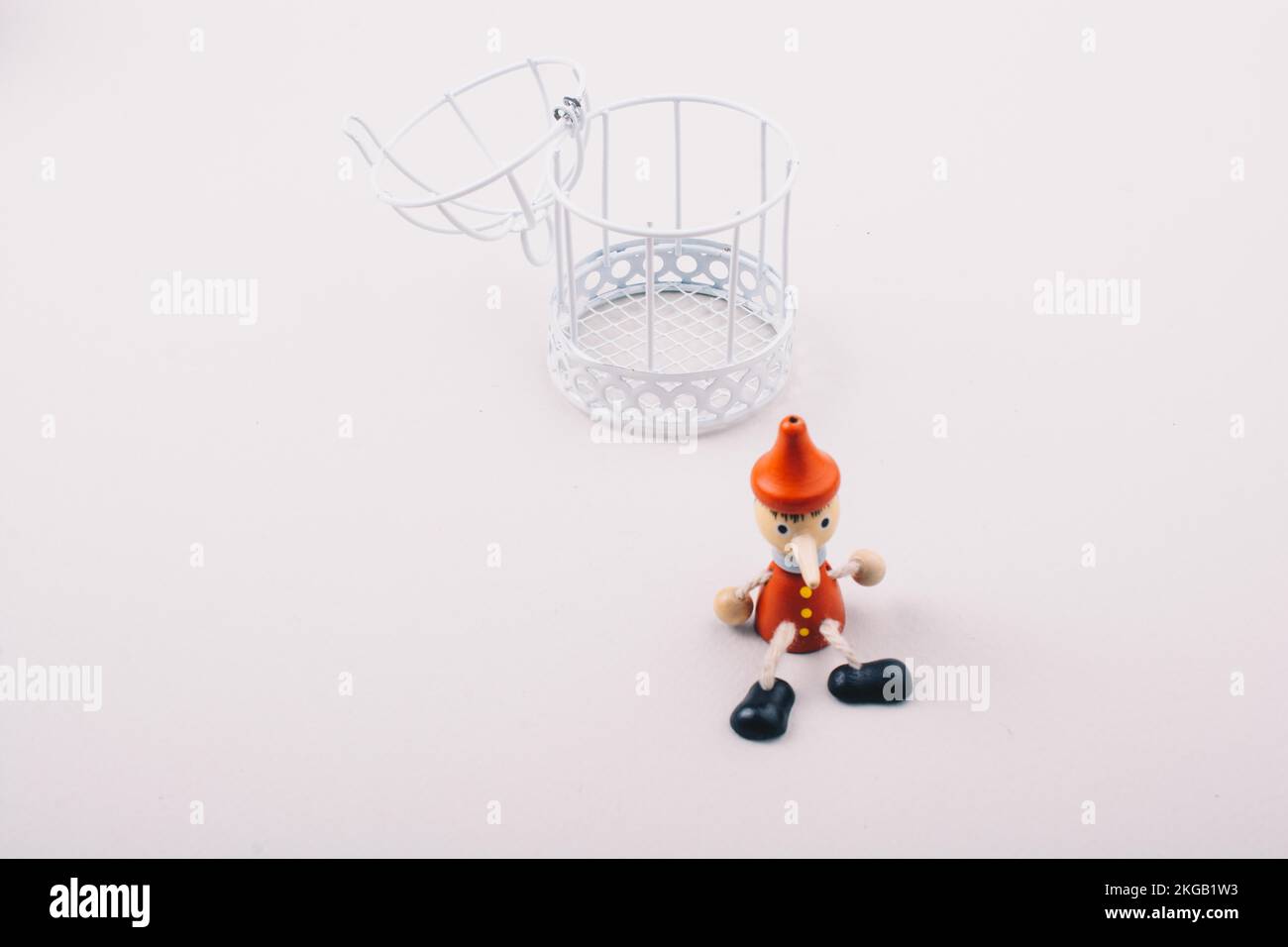Metal cage and Little puppet pinocchio made of wood Stock Photo - Alamy