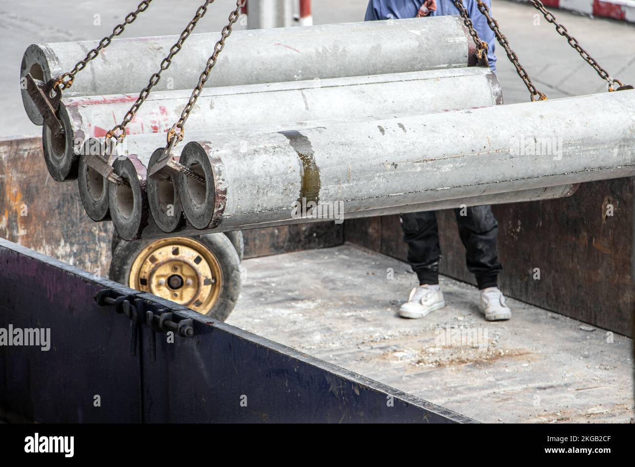A crane lifts concrete tubes from the load space of a truck Stock Photo ...