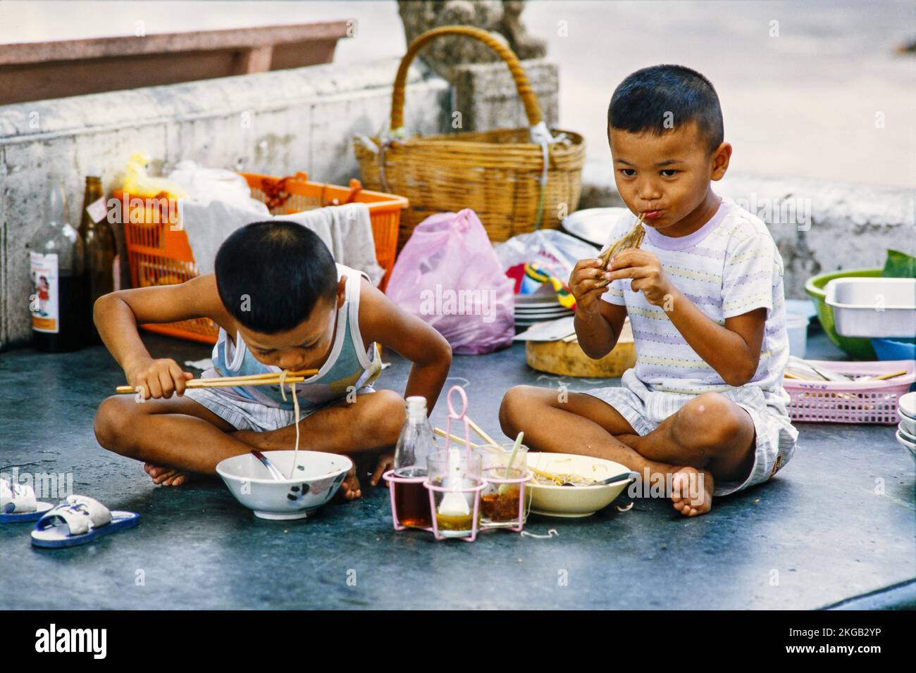 Boys eating noodle soup and chicken at the Wat Pho temple, picnic ...